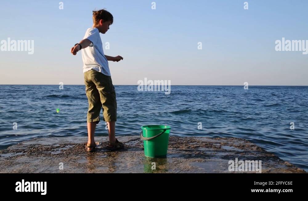 Boy teen with fishing rod and bucket fishing in sea with horizon Stock ...
