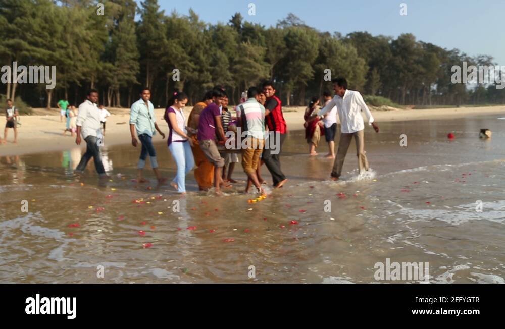 Group of people carrying religious statue to water at beach in Goa ...