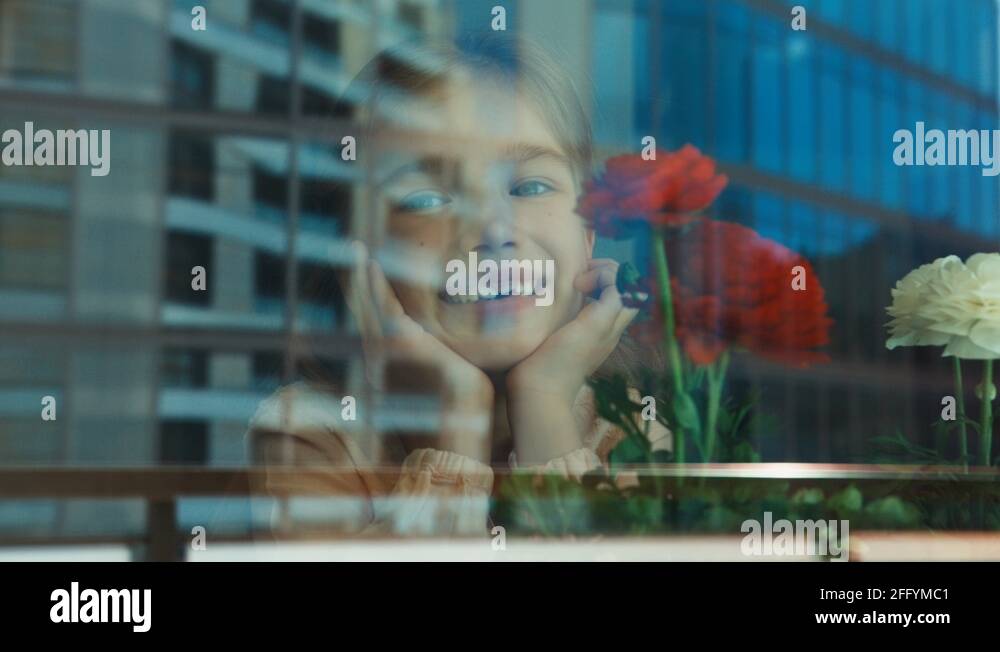 Little girl looking out the window and smiling. Filming through the ...