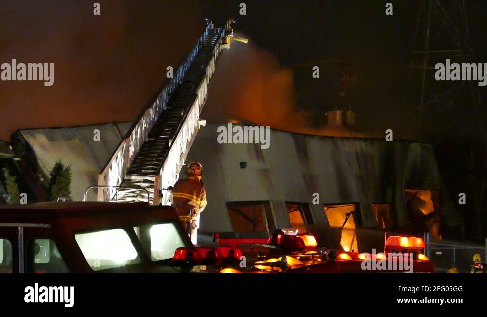 Fireman putting water on commercial building fire with aerial ladder ...