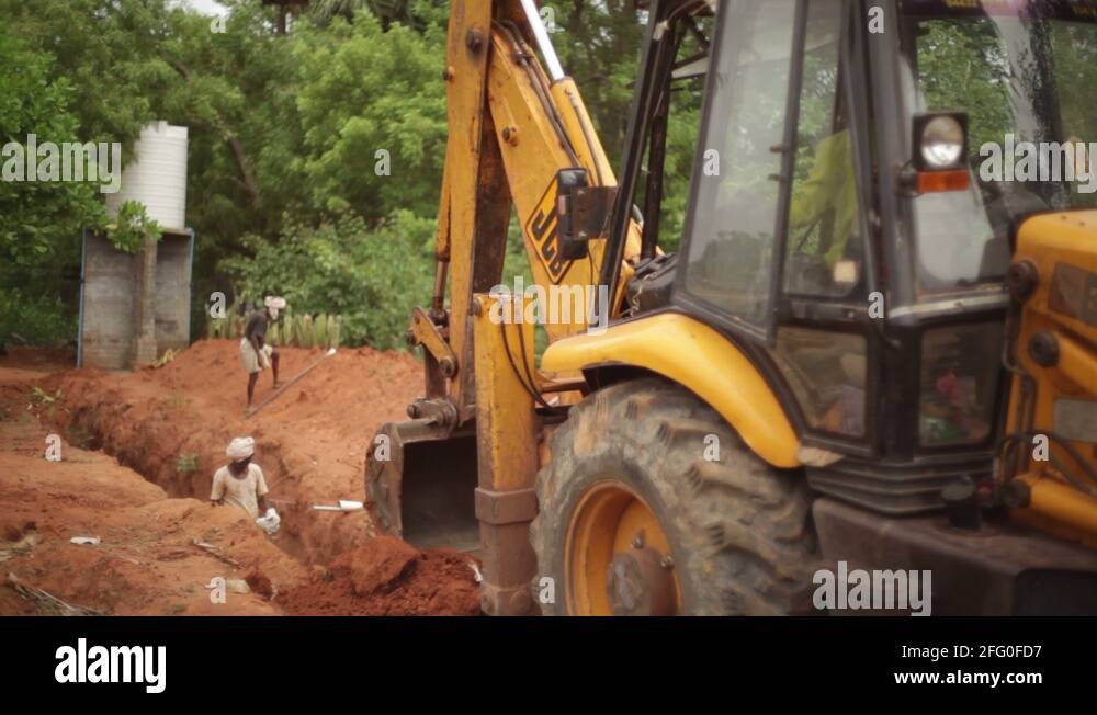 JCB Bulldozer tractor digging soil with Indian worker in background 6 ...
