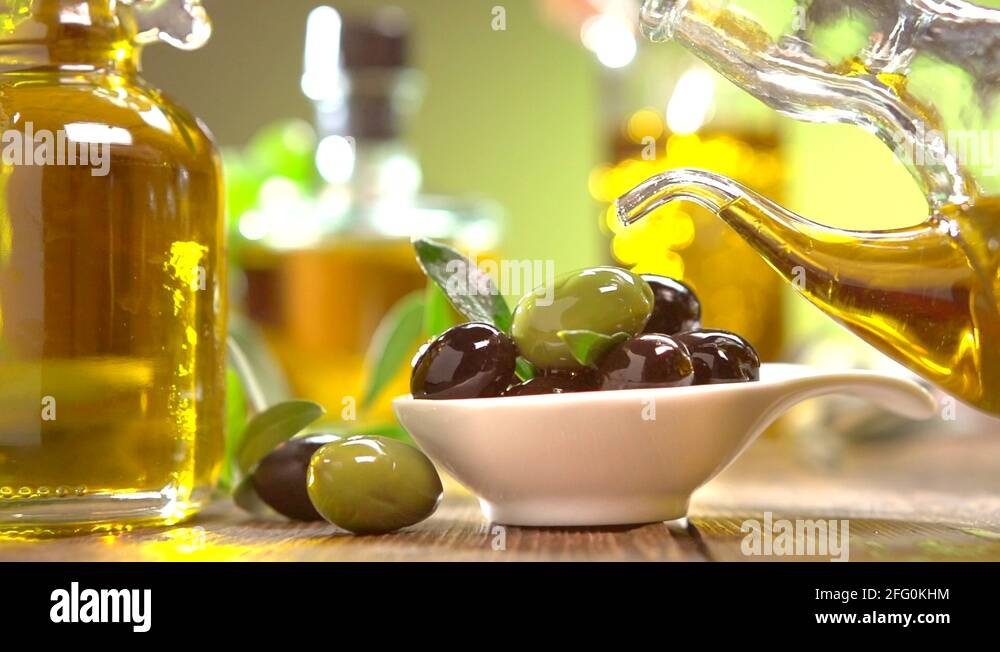 Olives and pouring olive oil. Extra virgin olive oil pouring from a jar ...