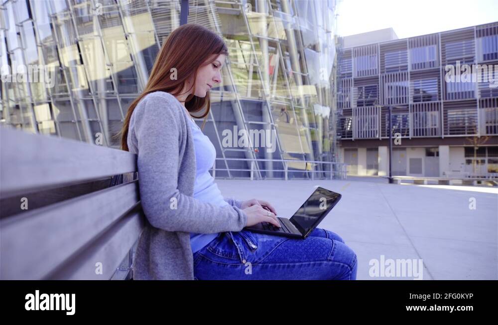 Female student with laptop on legs in front of school 4K Stock Video ...