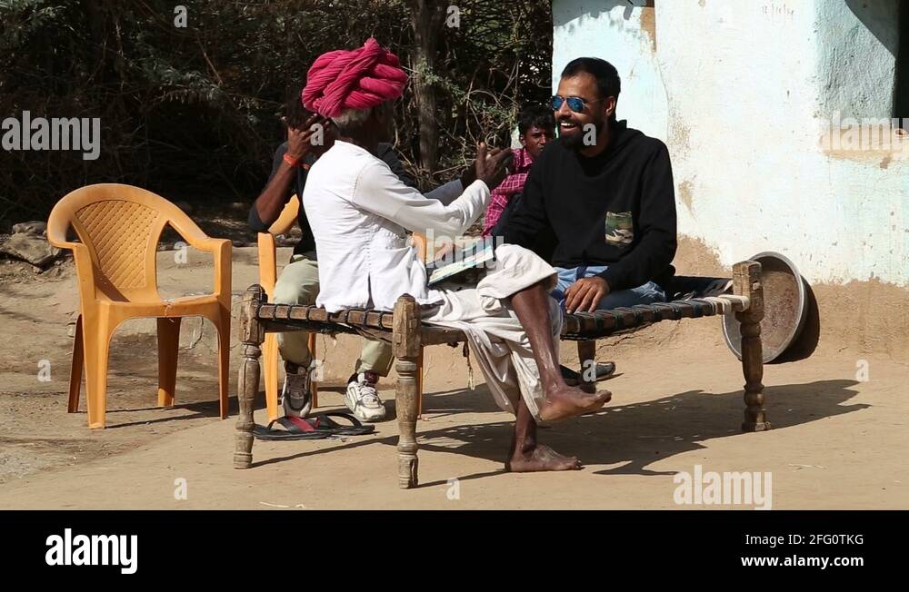 Young and old Indian man sitting on bench and cheerfully talking Stock ...