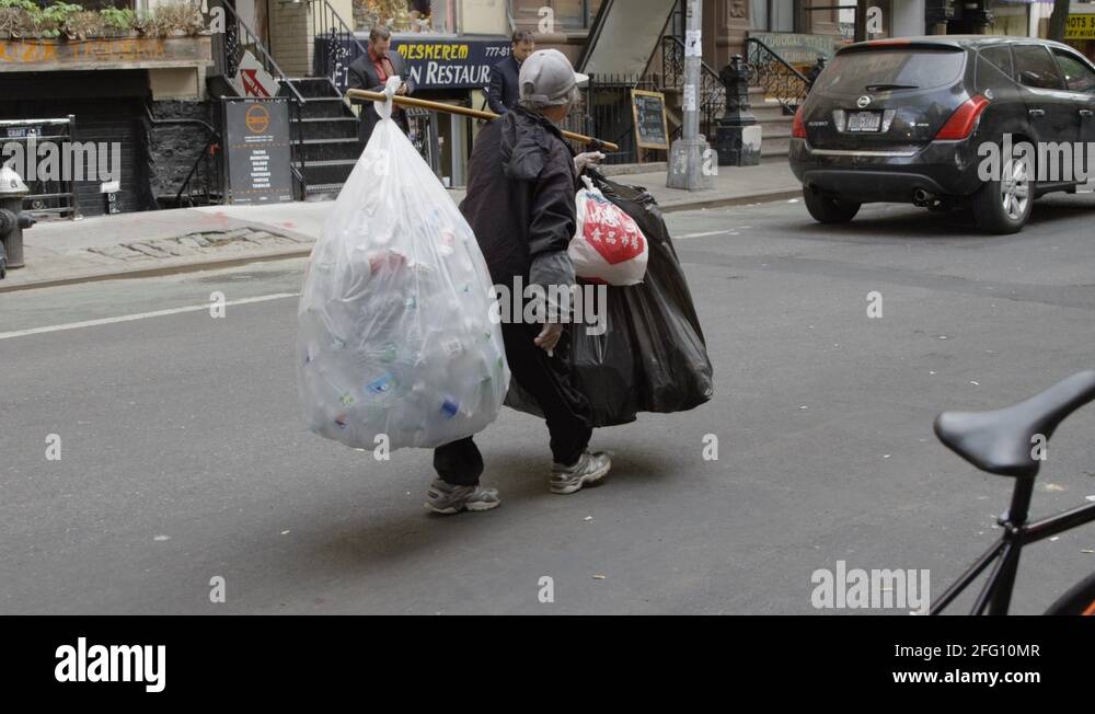 homeless Asian lady carrying plastic bags filled empty cans slow motion ...