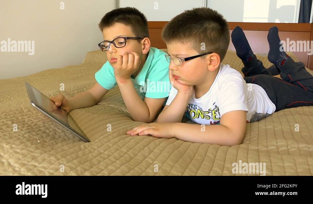 Boys lying on the bed and use a tablet computer Stock Video Footage - Alamy