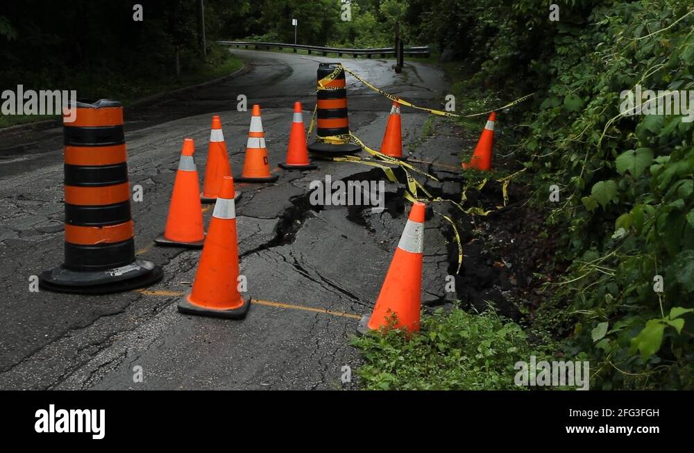 Orange pylons warning of road damage due to flood erosion Stock Video ...