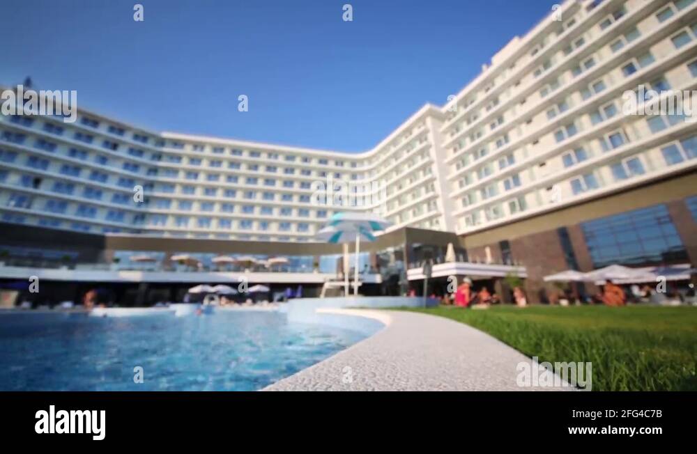 Green grass, pool border and people resting near pool of hotel Stock ...