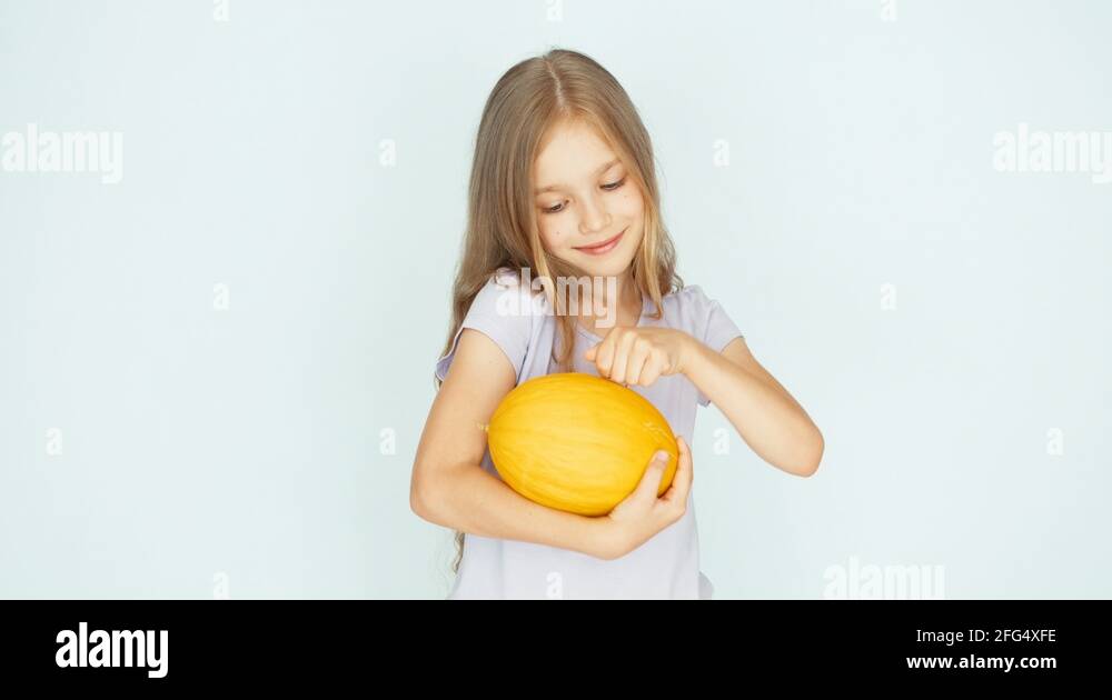 Girl playing with melon and laughing at camera on the white background ...