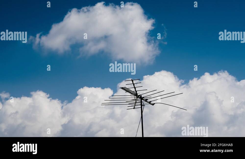 Old rooftop TV antenna white clouds blue sky background. 4K UHD ...