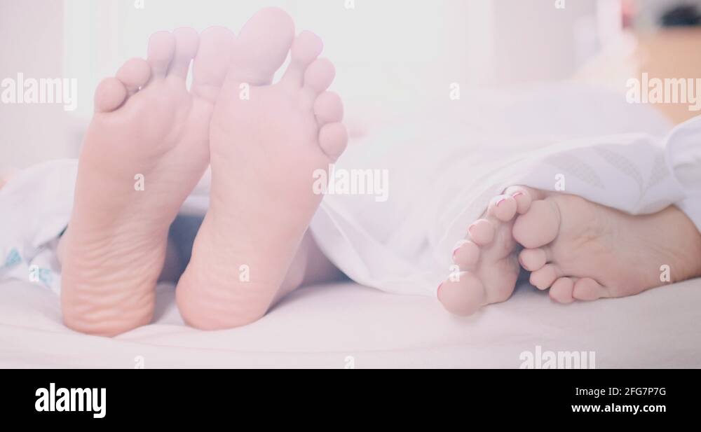 Pair of feet playing footsie at home in bed. Slow Motion, 4K. Lens ...