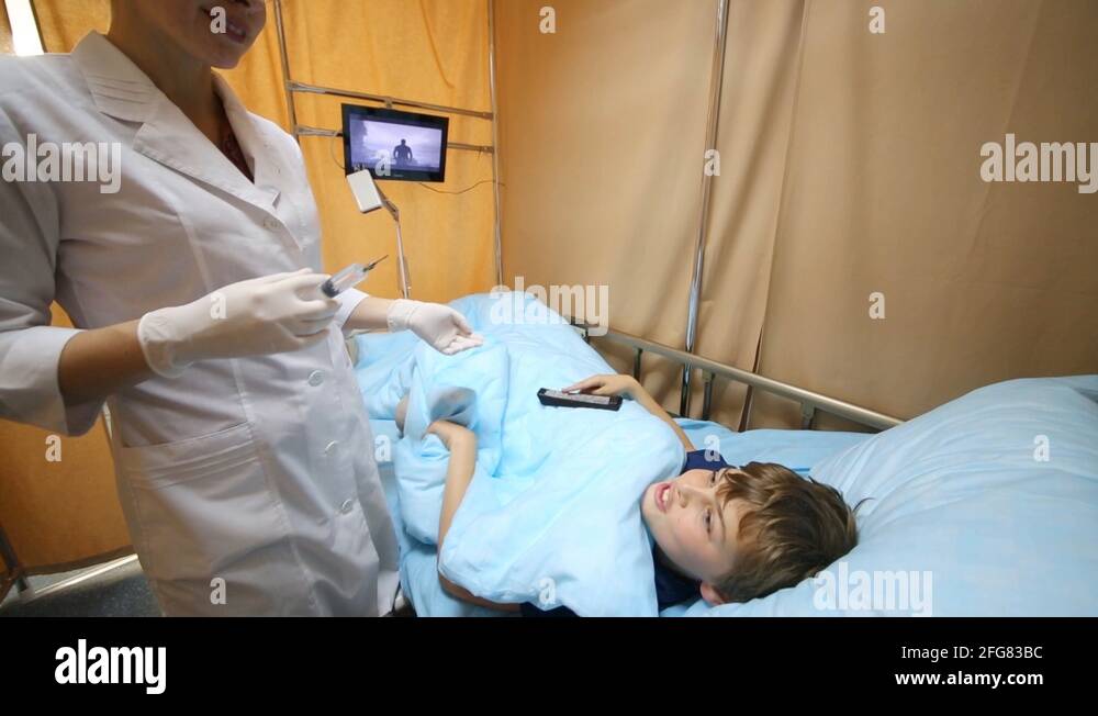 Hospital ward, boy lies and female health worker with syringe Stock ...