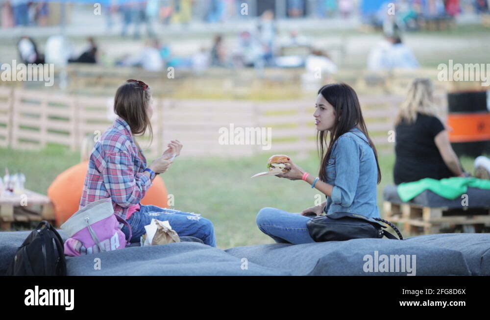 two beautiful girls eating burgers at the festival of street food Stock ...