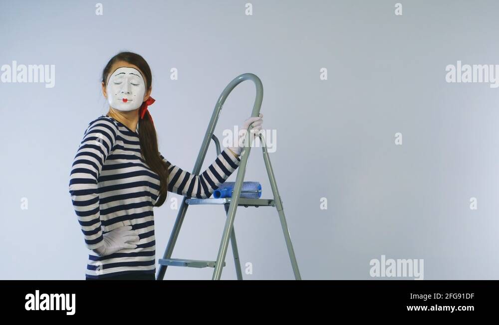 Woman mime standing on a ladder and paint the invisible wall Stock ...