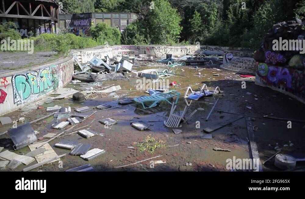 Chairs and trash in an abandoned empty outdoor pool, graffiti Stock ...