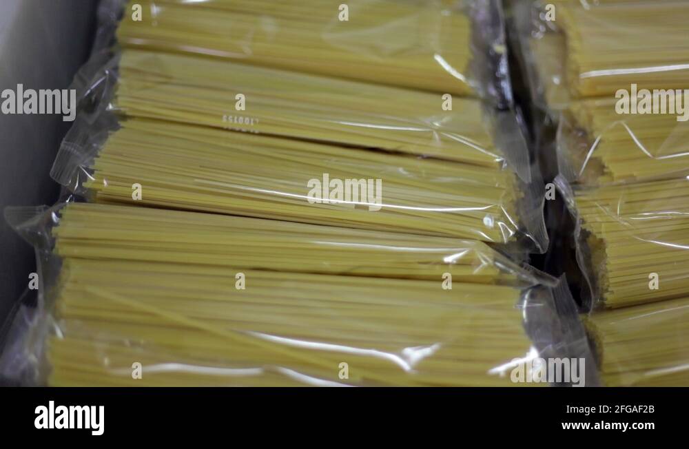 Dolly shot of spaghetti bags storing into plastic container in a pasta ...