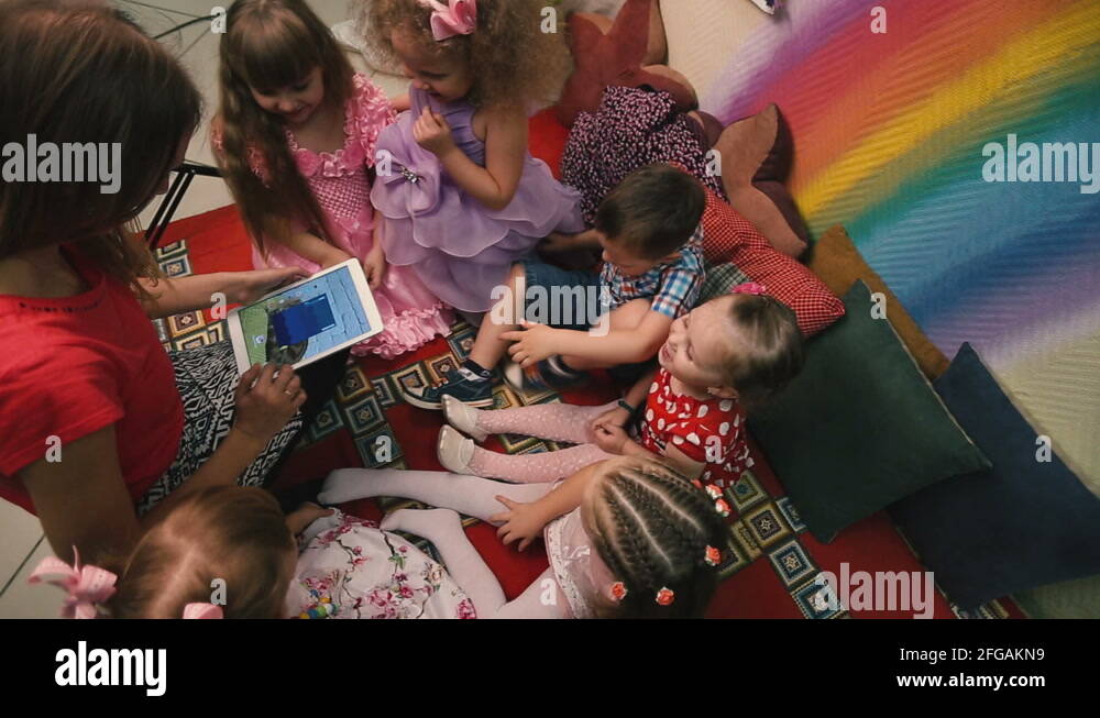 A young girl shows children playing on a tablet Stock Video Footage - Alamy