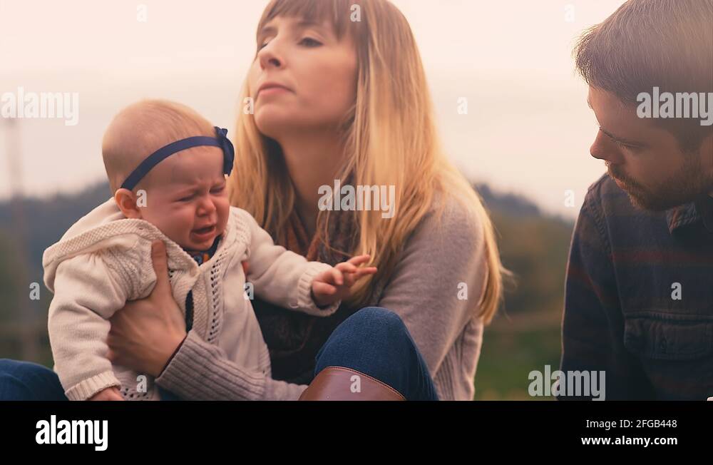 A mother tries to calm her crying baby while out on a family picnic ...