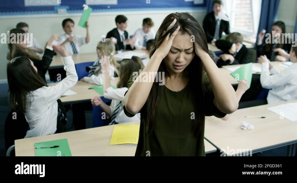 4k, Portrait of a frustrated young teacher in a classroom full of ...