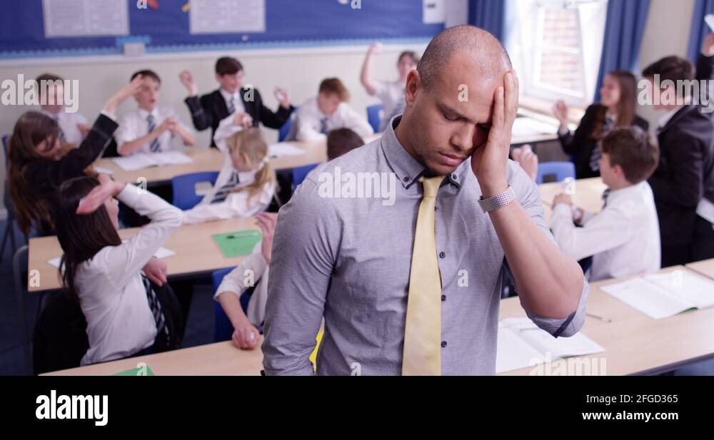 4k, Portrait of a frustrated young teacher in a classroom full of ...