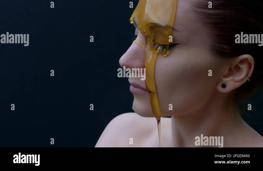 4k shoot of a model in studio with honey pouring on her face in reverse ...