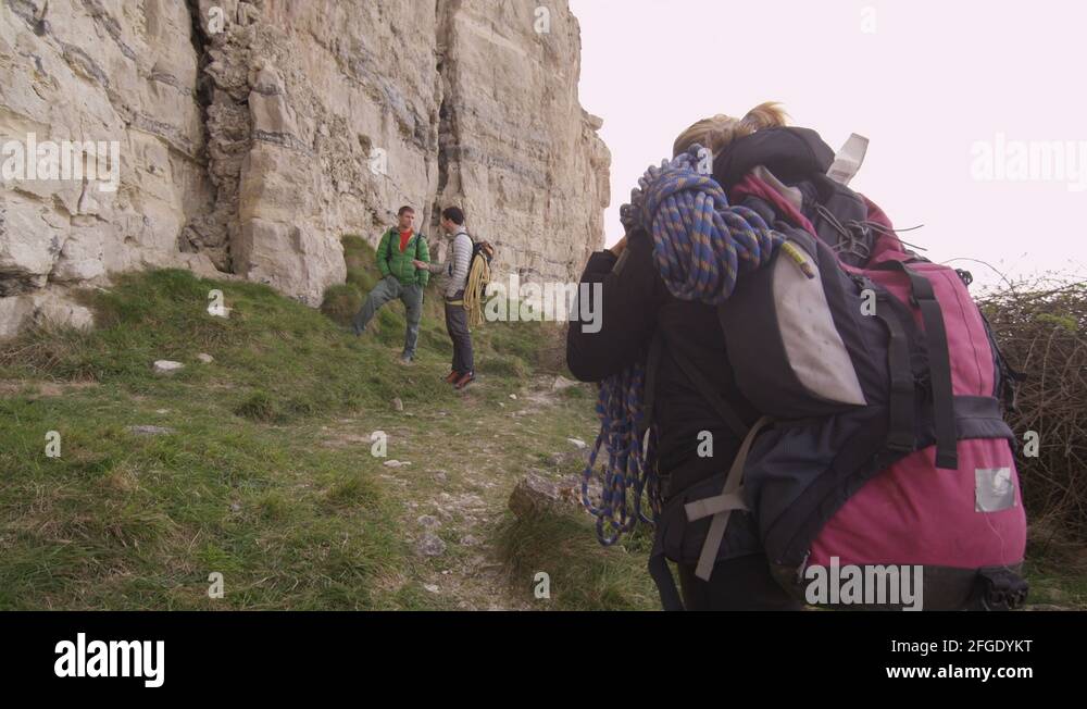 4K Group of rock climbers standing at base of cliff & planning their ...