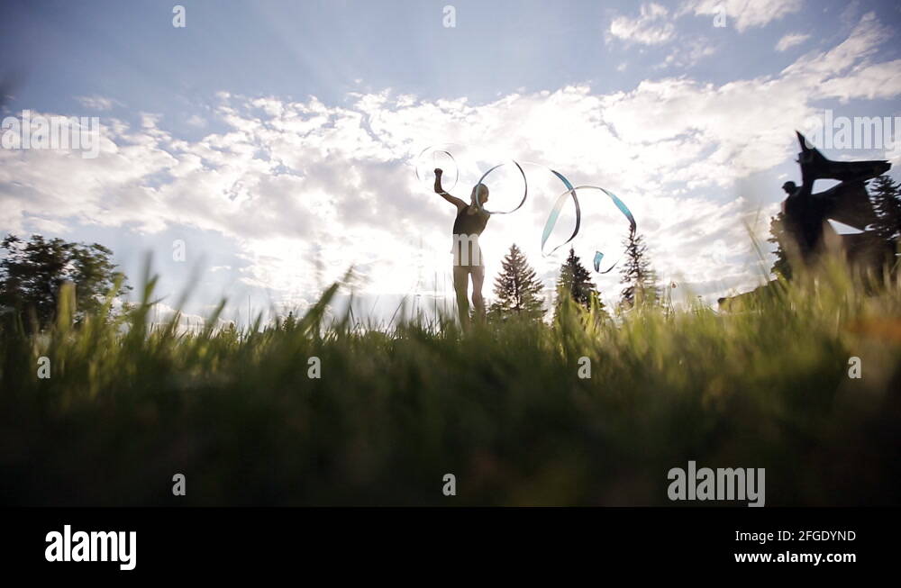 Dance young gymnast with ribbon on sunset sky background. Rhythmic ...