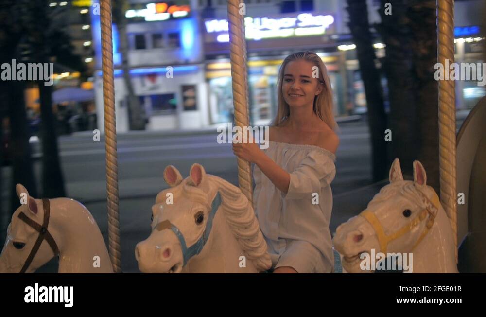 Beautiful delicate girl with hat smiling in a carousel on her vacation ...