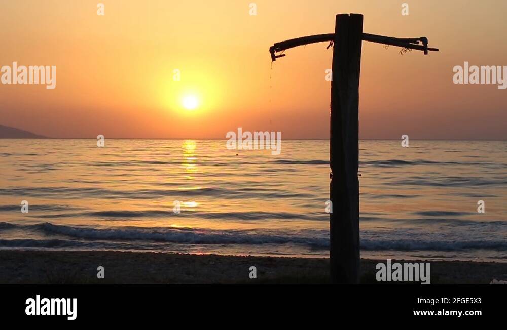 A shower dripping on the beach in silhouette at sunset Stock Video ...