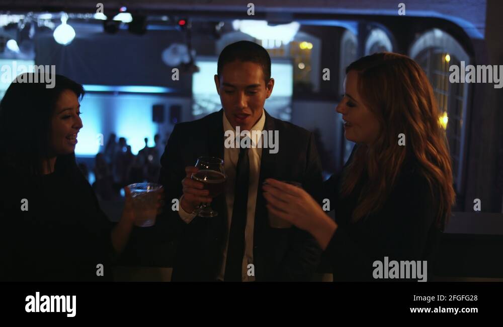 friends in the balcony of a nightclub toast their drinks and start ...