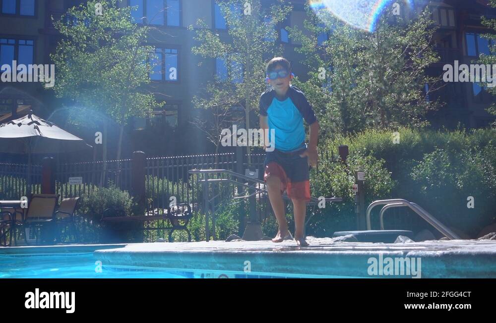 A boy jumps and does a cannonball into a pool at a hotel resort Stock ...