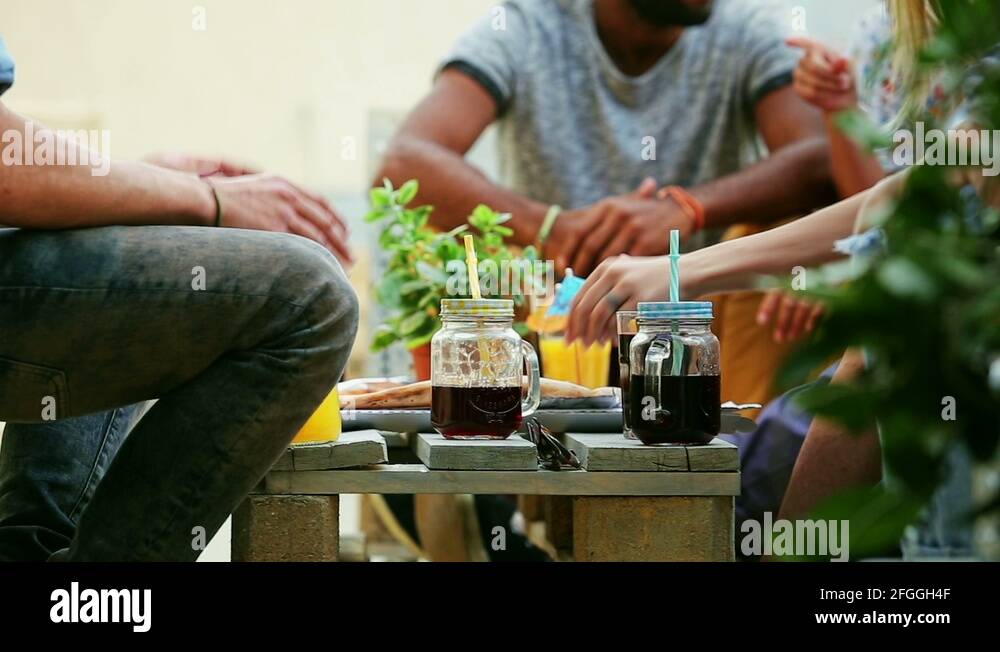 Mid-section of people sitting around table eating pizza and drinking ...