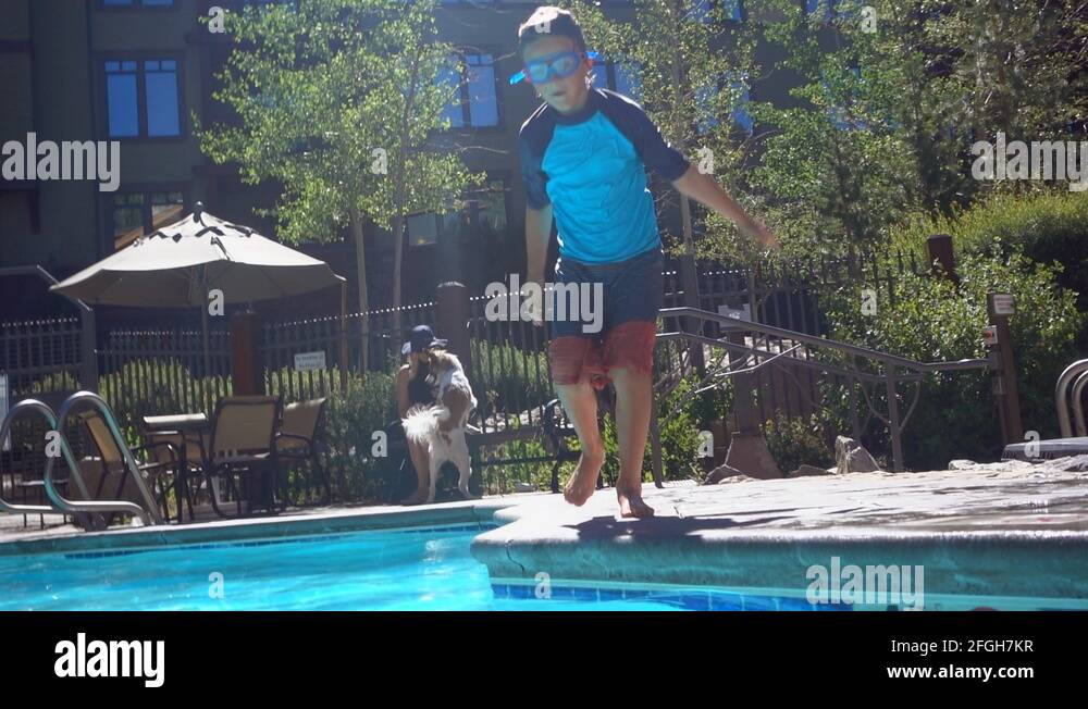 A boy jumps and does a cannonball into a pool at a hotel resort Stock ...