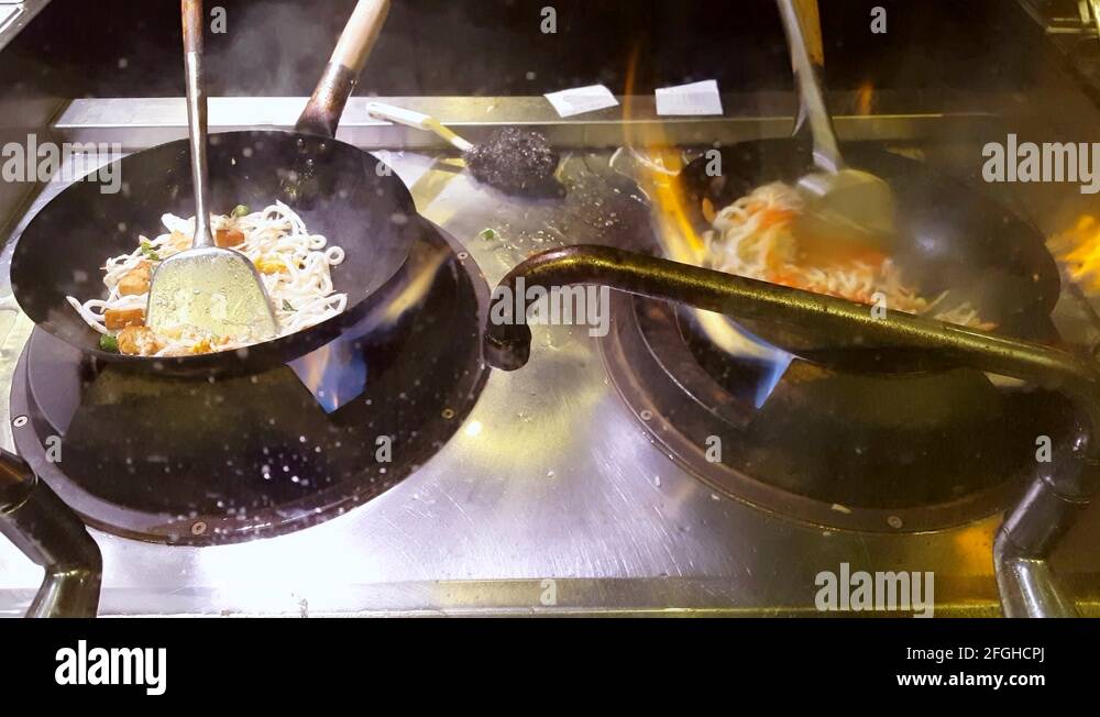 Frying noodles and vegetables in big Asian wok pan, fast food ...