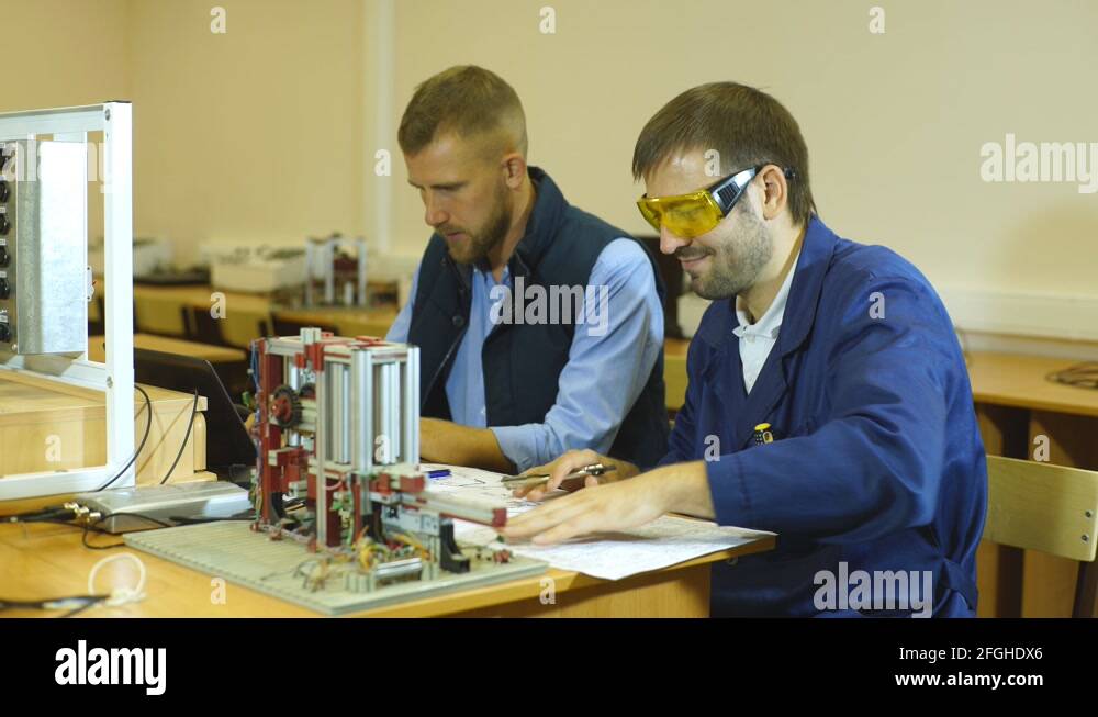 Engineering working in the lab, adjusting a 3D printer's components ...