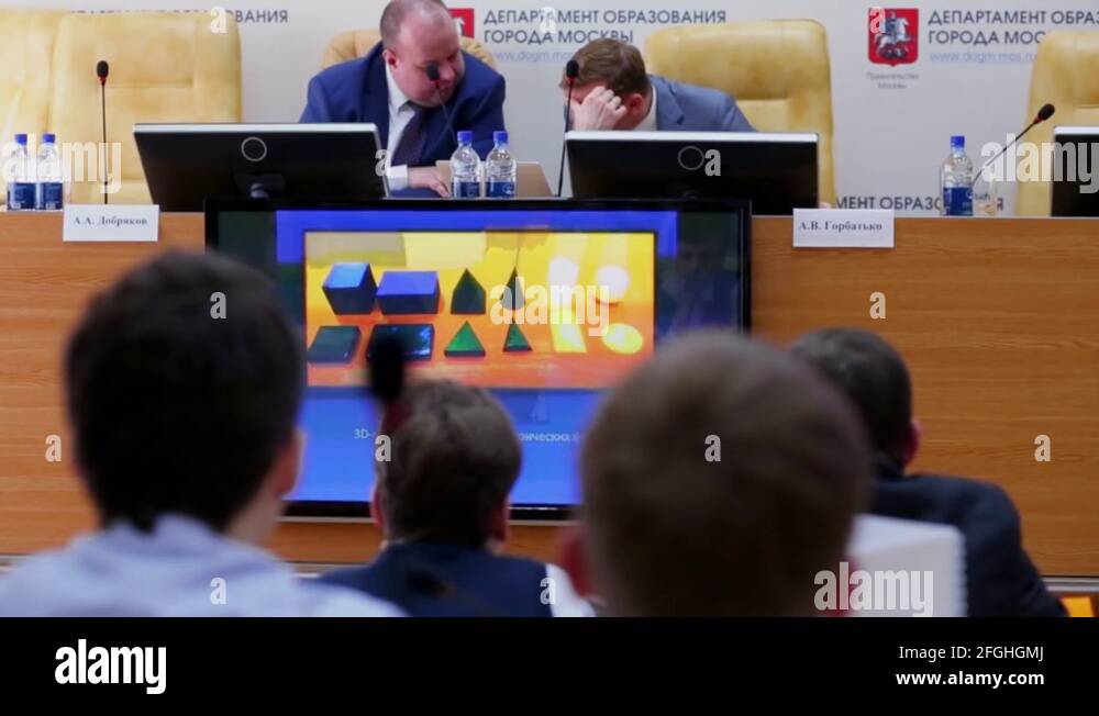 Students watch presentation on screen at presidium desk during IT ...