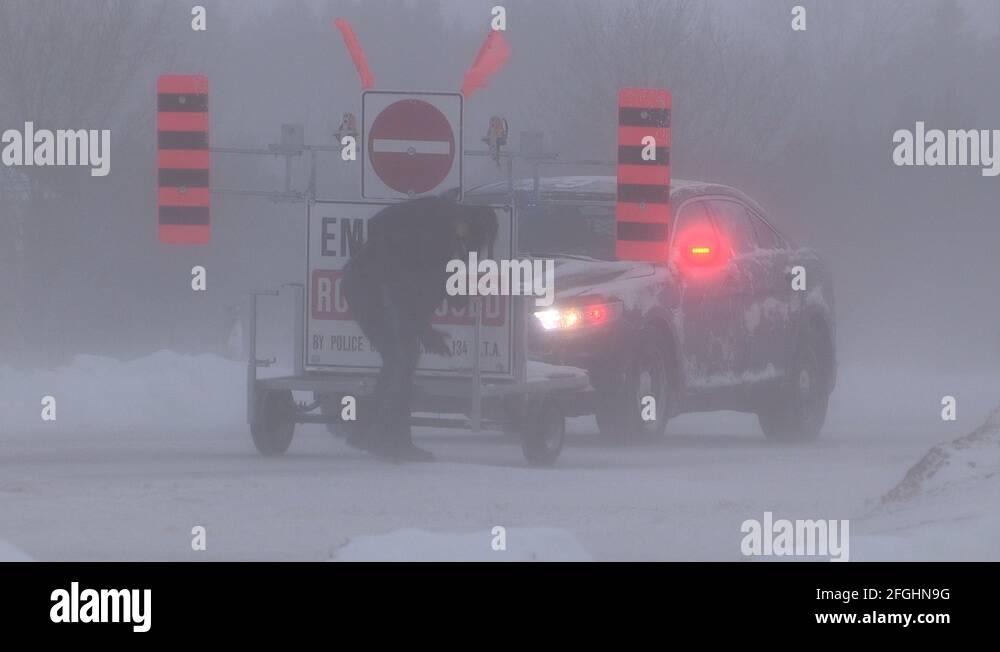 Road closed sign and police car with flashing lights in snow storm ...