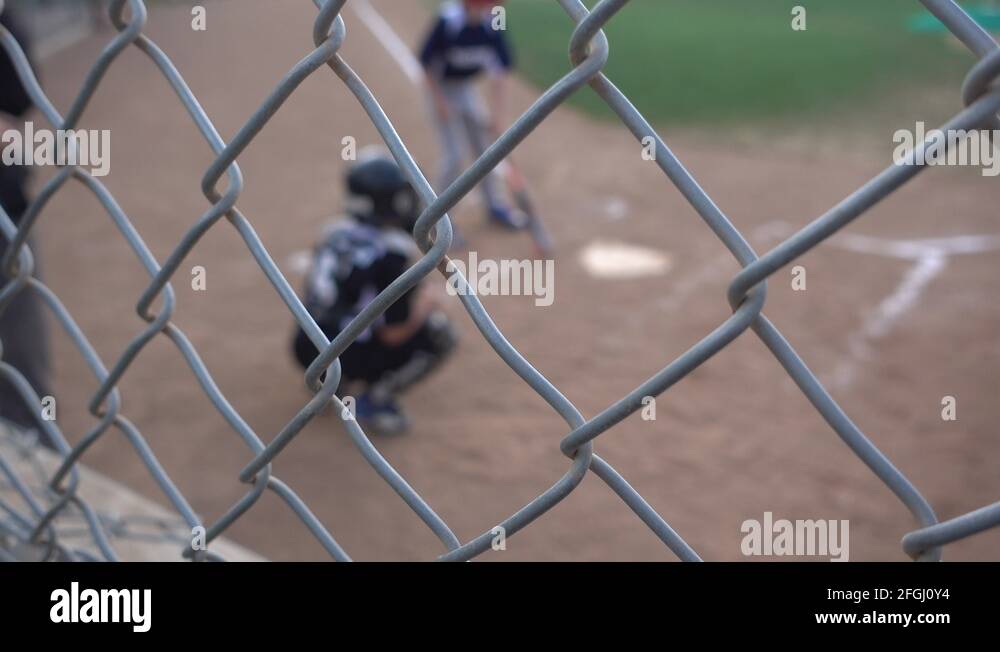 Boys playing in a little league baseball game through a chain-link ...