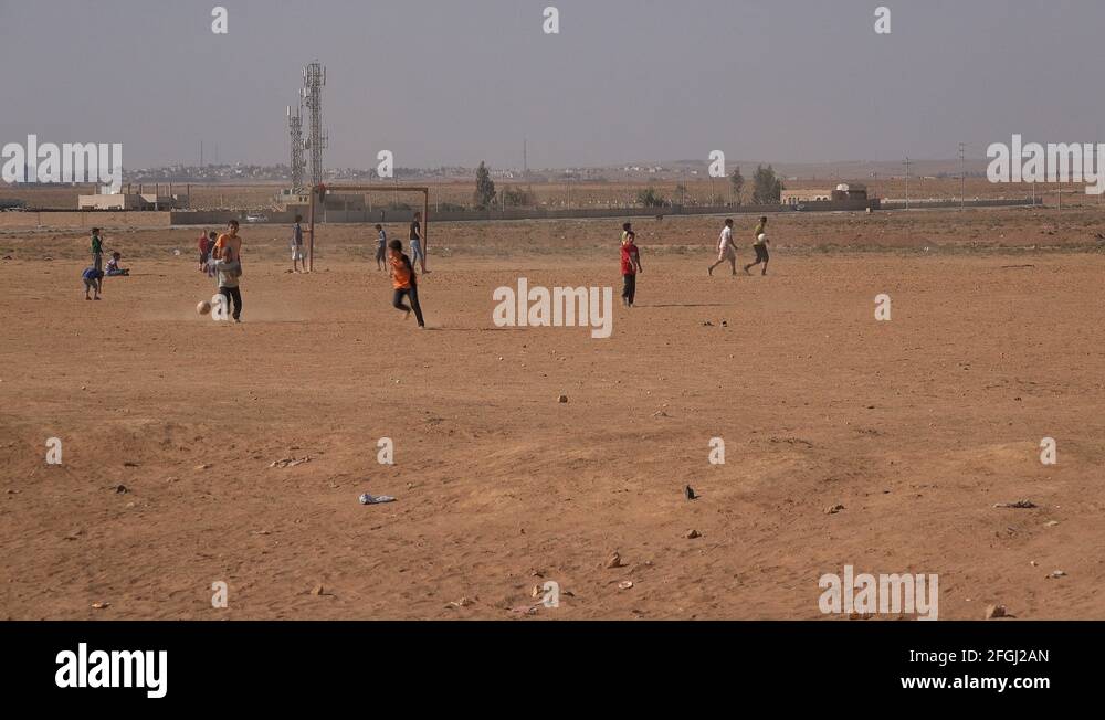 Syrian refugees play football (soccer) on a dry pitch in Zaatari camp ...