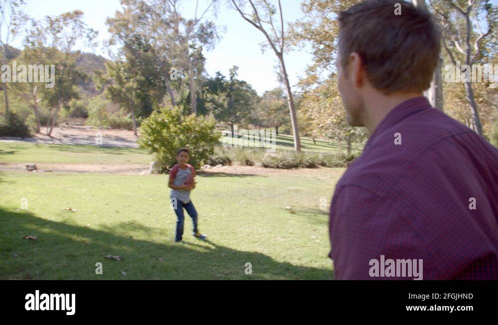 Seven year old boy throwing football with his dad in park Stock Video ...