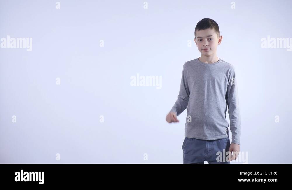 A smiling little boy shows his finger to the side against the white ...