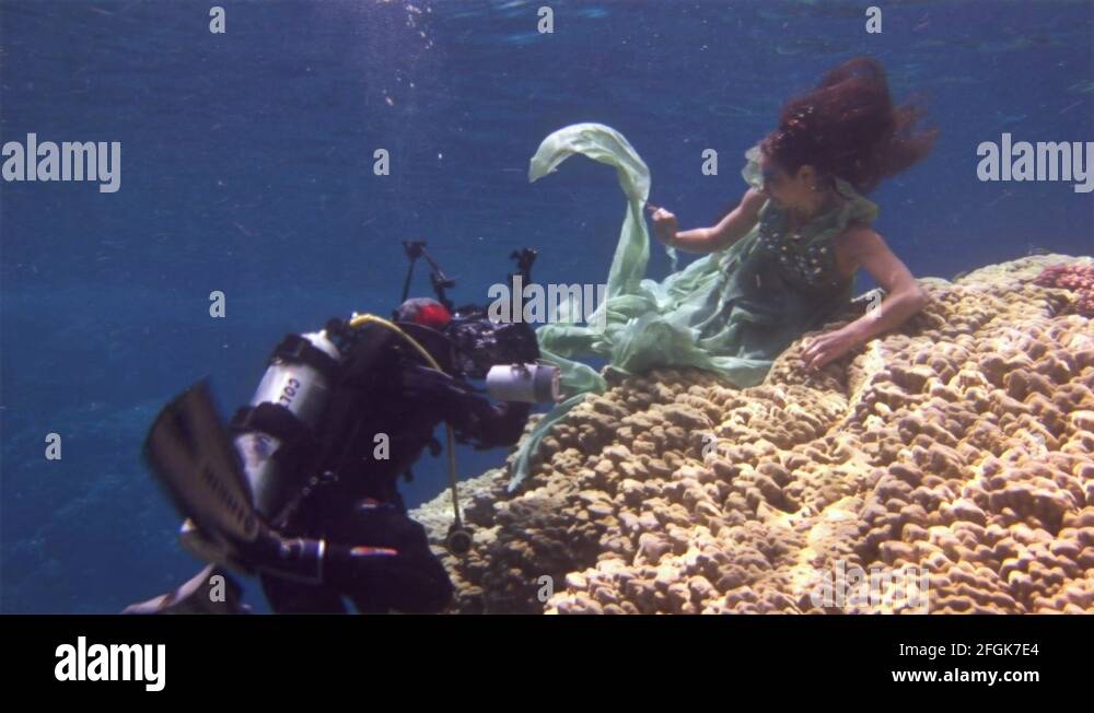 Underwater model free diver poses for camera on background of corals in ...