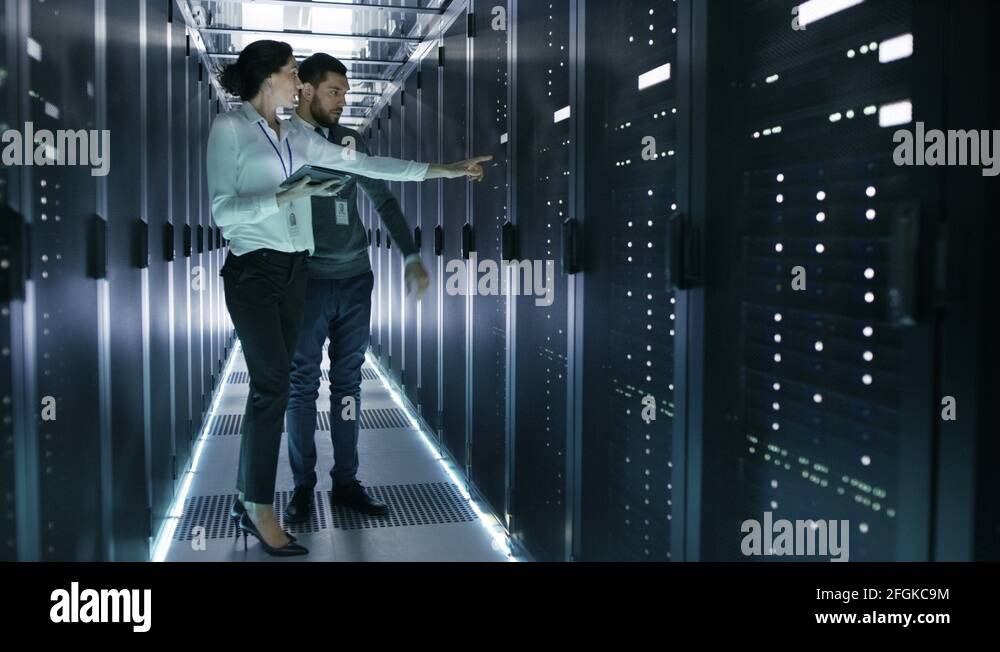 Male and Female Server Technicians Working in Data Center. Running Rack ...