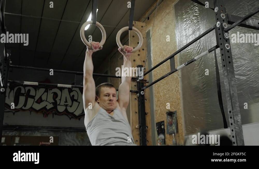 Male man athlete working out his muscles on rings, crossfit acrobat ...