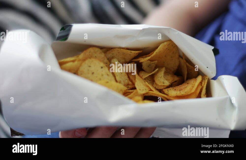 Boy teenager eating potato chips with hands on sofa at home unhealthy ...