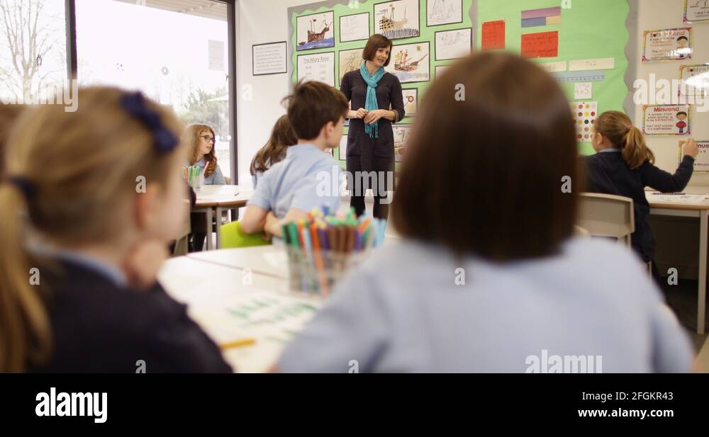 4K Primary school teacher talking to class of young children & asking ...