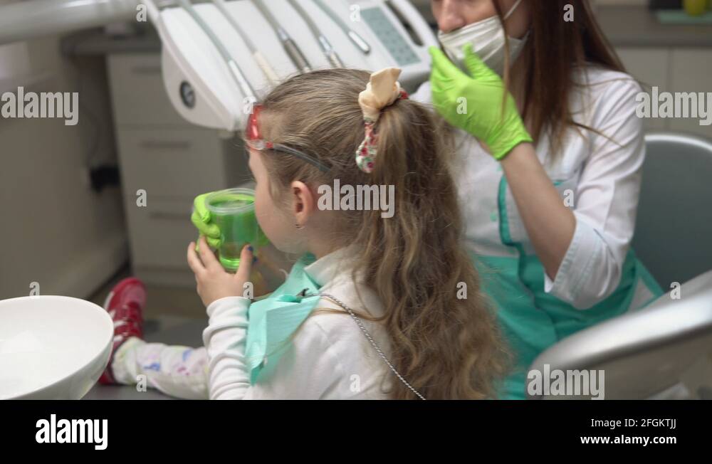 Little cute girl rinsing her mouth with treatment at the dentist ...