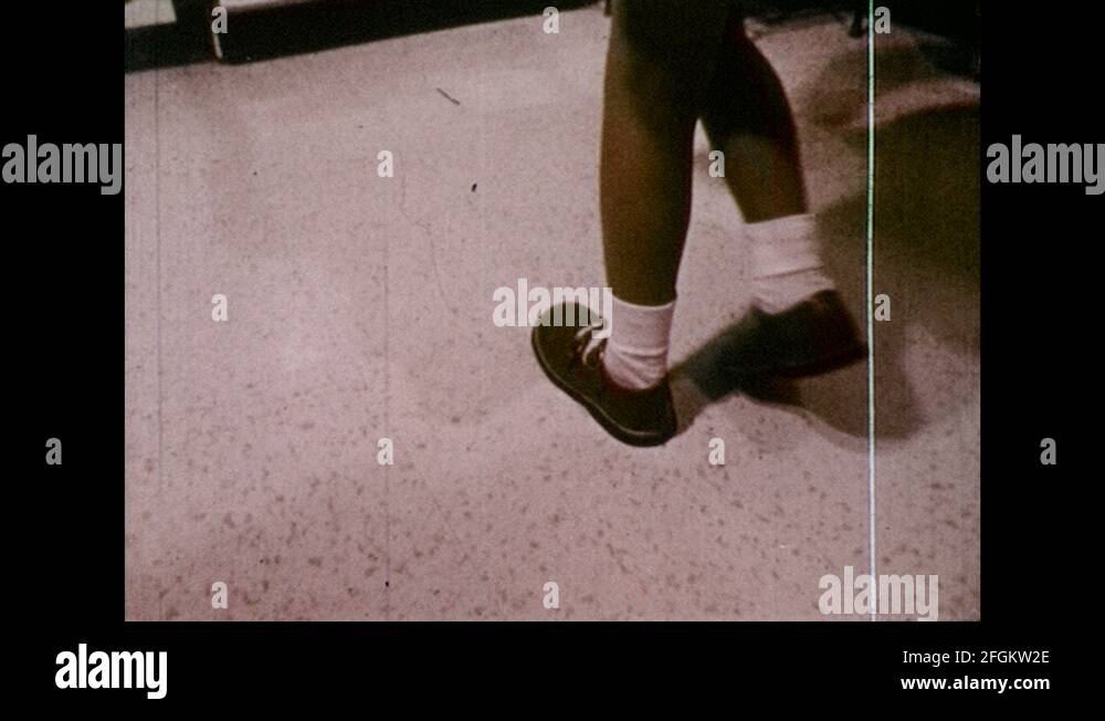 1970s: Girl's feet on kitchen floor, pan up, girl stacks stools, climbs ...