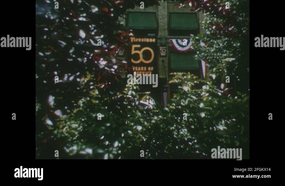1950s: View of banner, pan up to tower / Crowd walks up hill toward ...