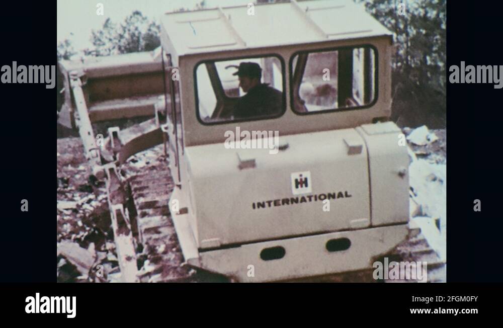 1970s – Trash is transferred by a bulldozer as a land next to several ...